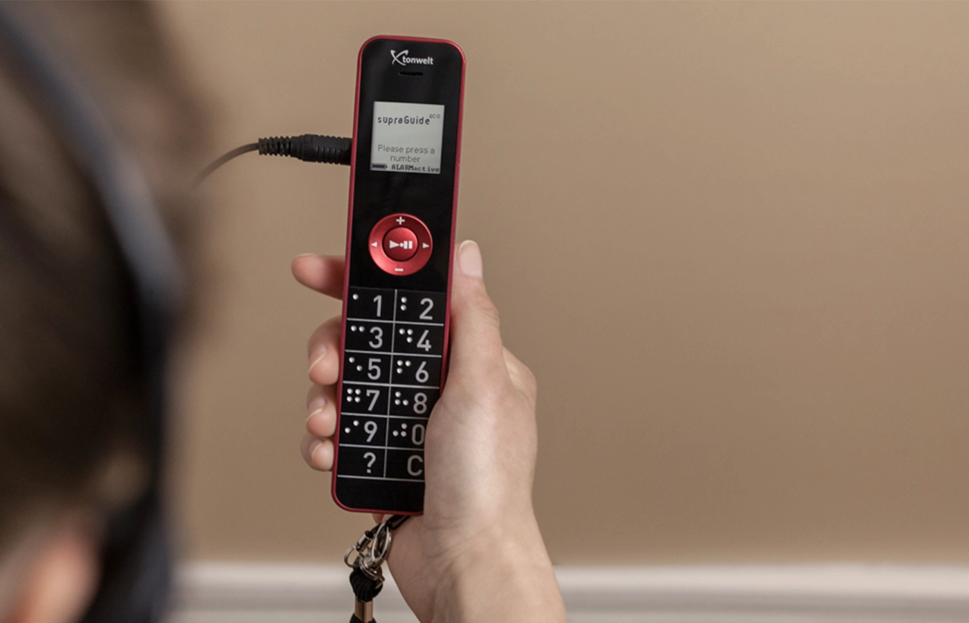 Close-up of a person holding a tonwelt supraGuide ECO, a portable audio ...